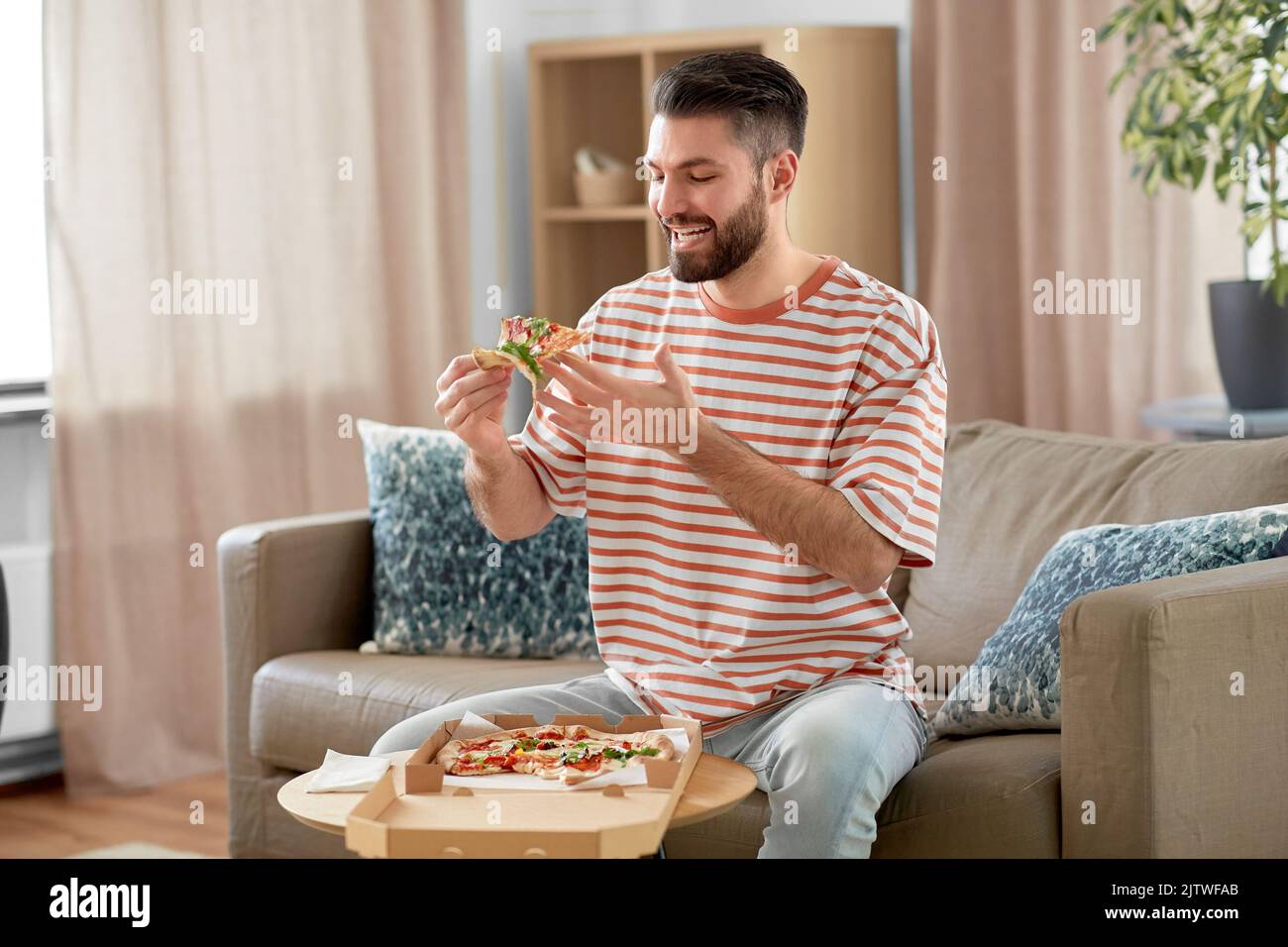 happy man eating takeaway pizza at home Stock Photo - Alamy