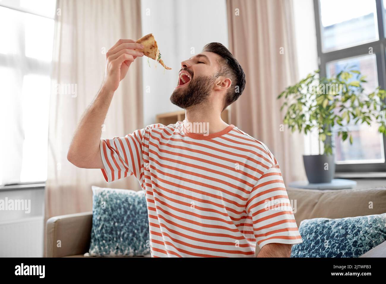 happy man eating takeaway pizza at home Stock Photo - Alamy