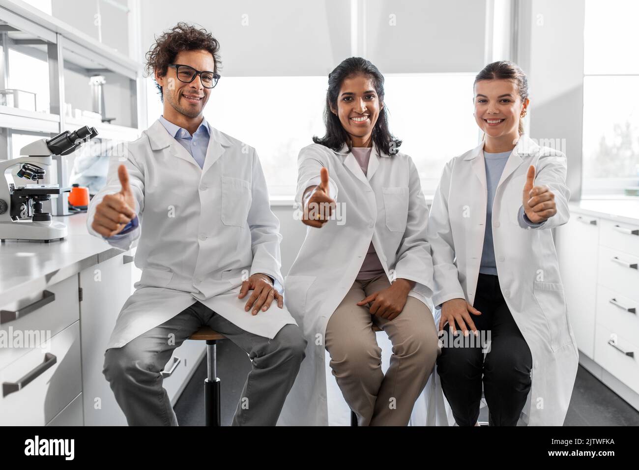 happy scientists showing thumbs up in laboratory Stock Photo - Alamy
