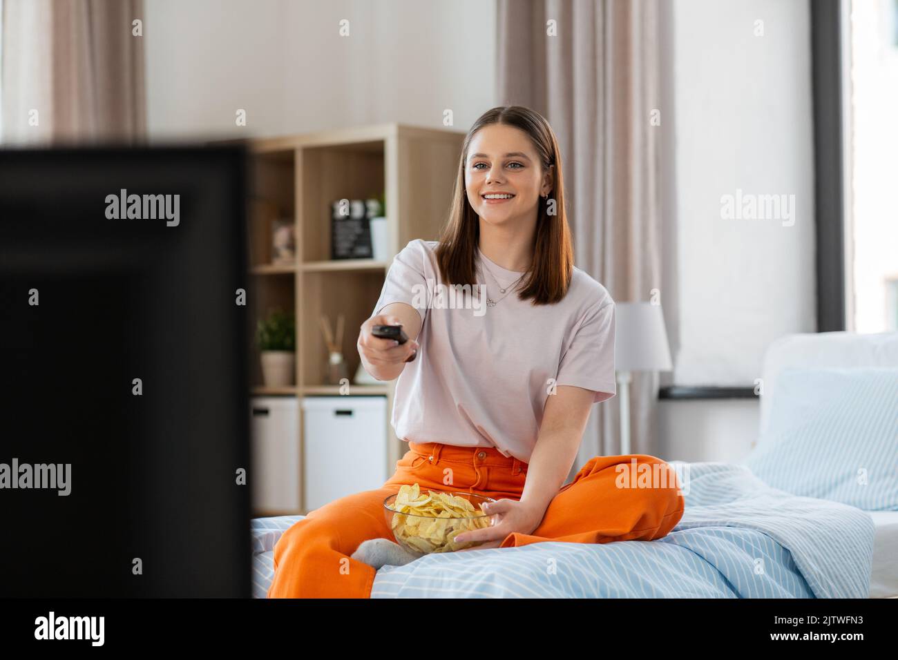 happy girl with crisps watching tv at home Stock Photo - Alamy