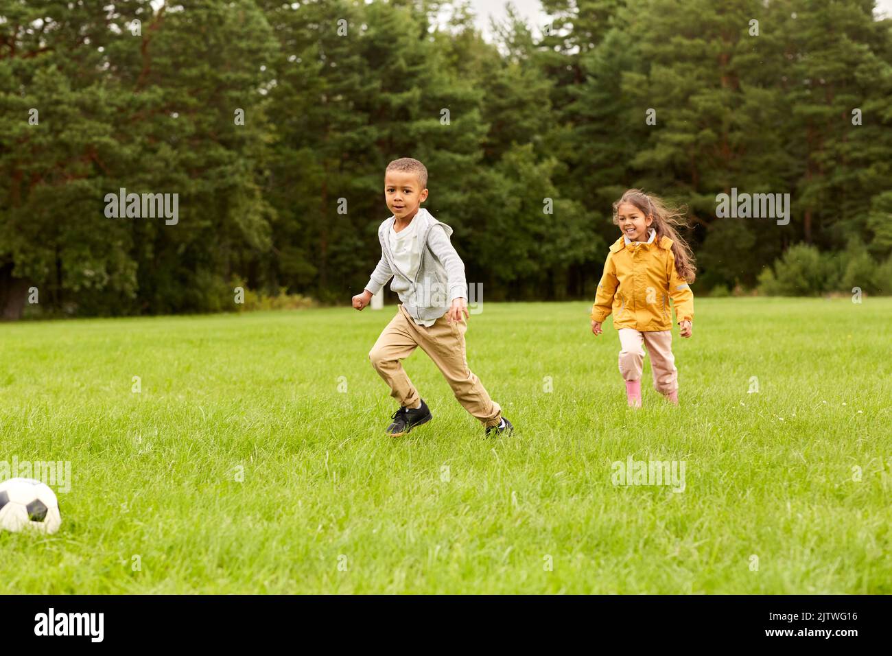 little children with ball playing soccer at park Stock Photo - Alamy