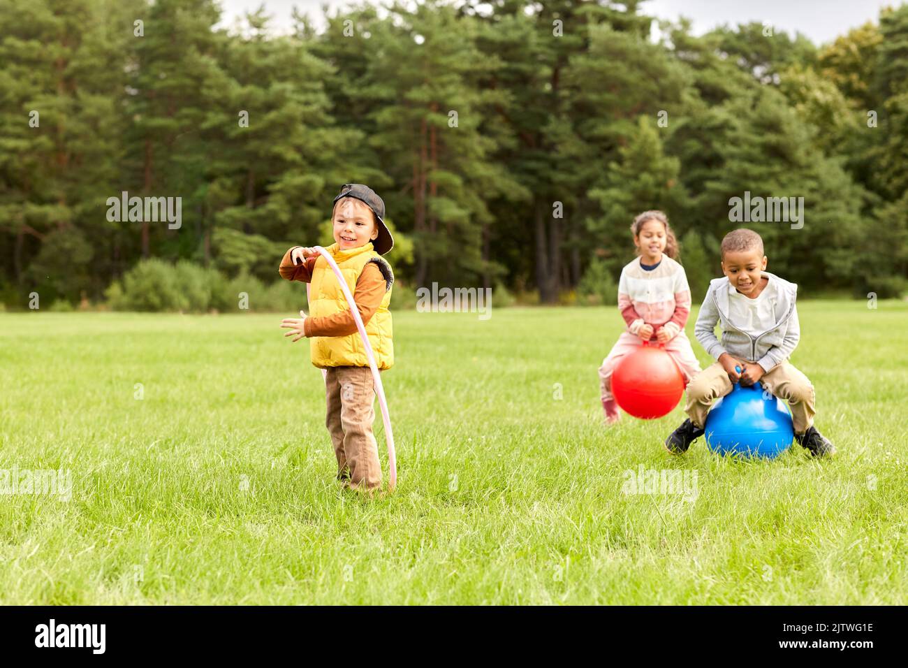 children playing with hoppers and hoop at park Stock Photo - Alamy