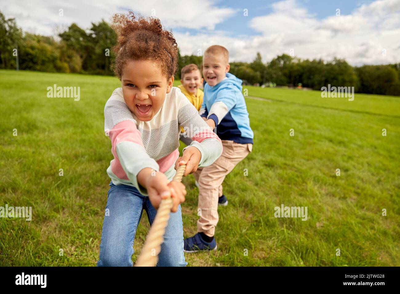 happy children playing tug-of-war game at park Stock Photo - Alamy