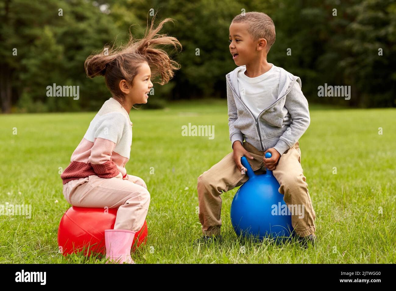 happy children bouncing on hopper balls at park Stock Photo - Alamy