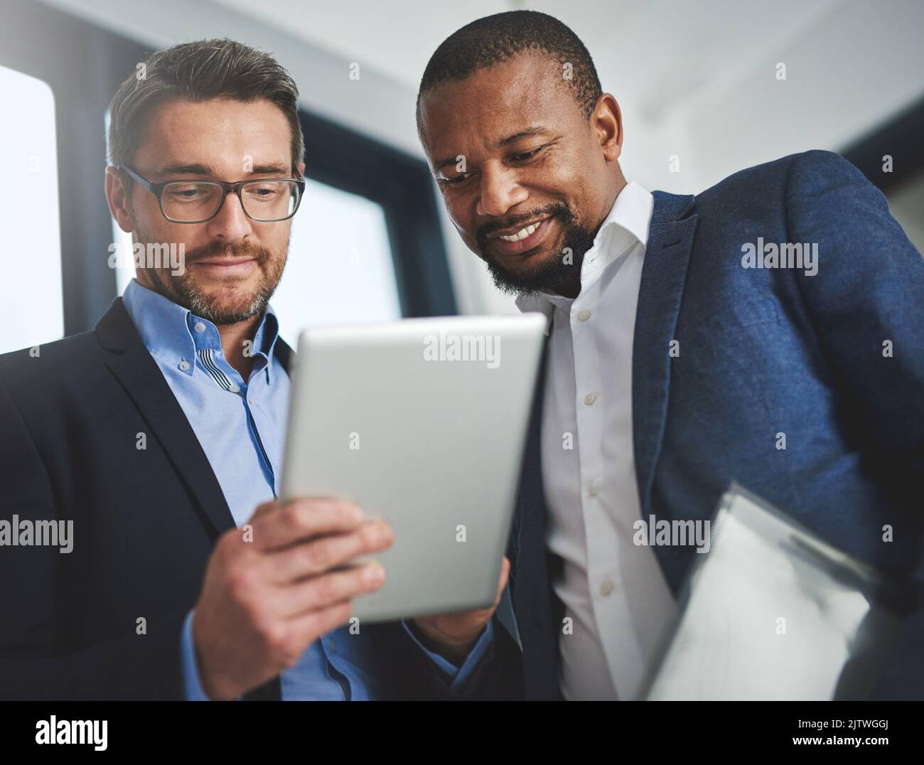 Less paper, more planning. two businessmen using a digital tablet ...