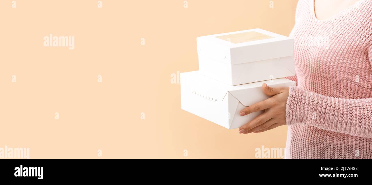 Woman holding cardboard boxes on beige background with space for text ...