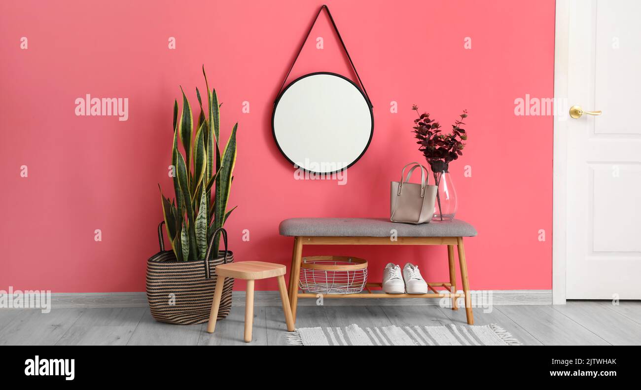 Interior of stylish hall with soft bench, stool, houseplant and mirror ...