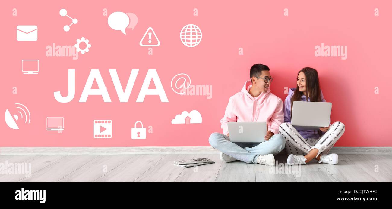 Couple of young programmers with laptops sitting near pink wall Stock ...