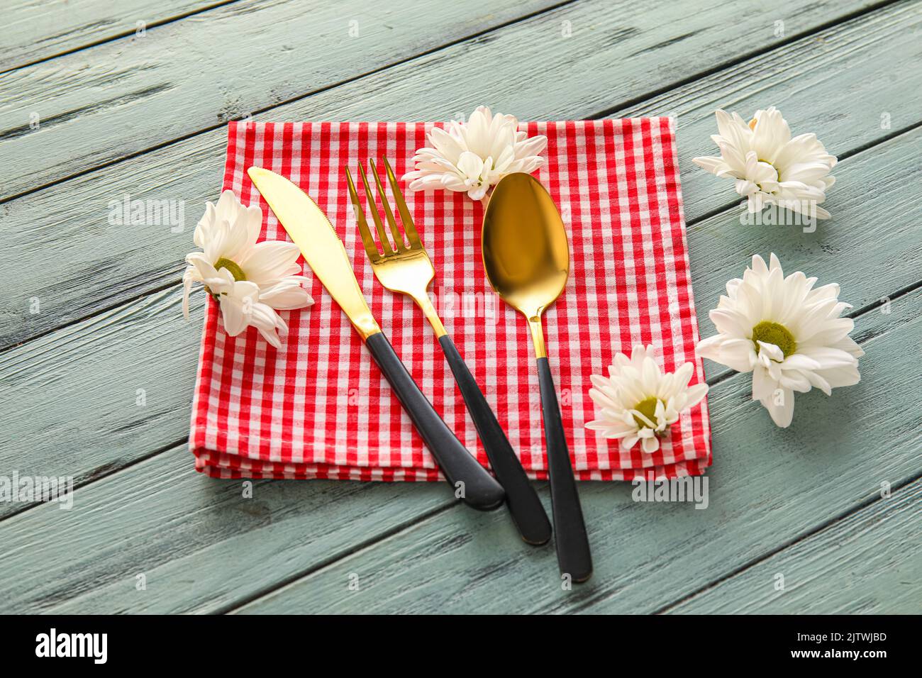 Cutlery, napkin and chamomile flowers on color wooden background Stock ...