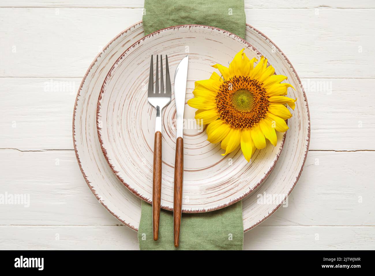 Simple table setting with cutlery and sunflower on white wooden ...