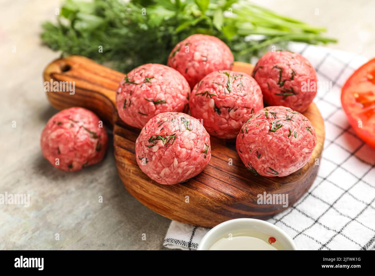 Cutting board with raw meat balls, herbs and napkin on grunge ...