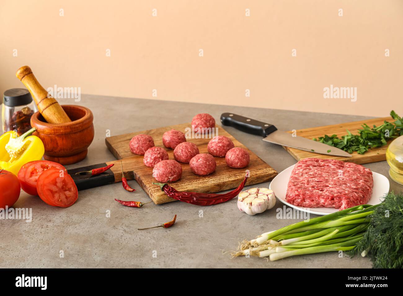 Cutting board with raw meat balls, plate of mince, spices and ...