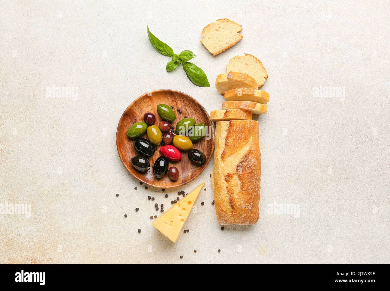Composition with plate of tasty olives, bread and cheese on light ...