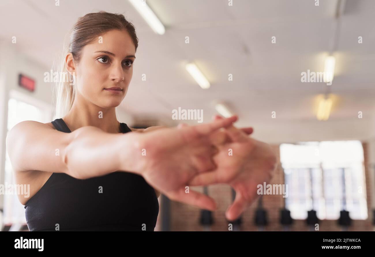 Lets get started. a young woman doing static stretches before working ...