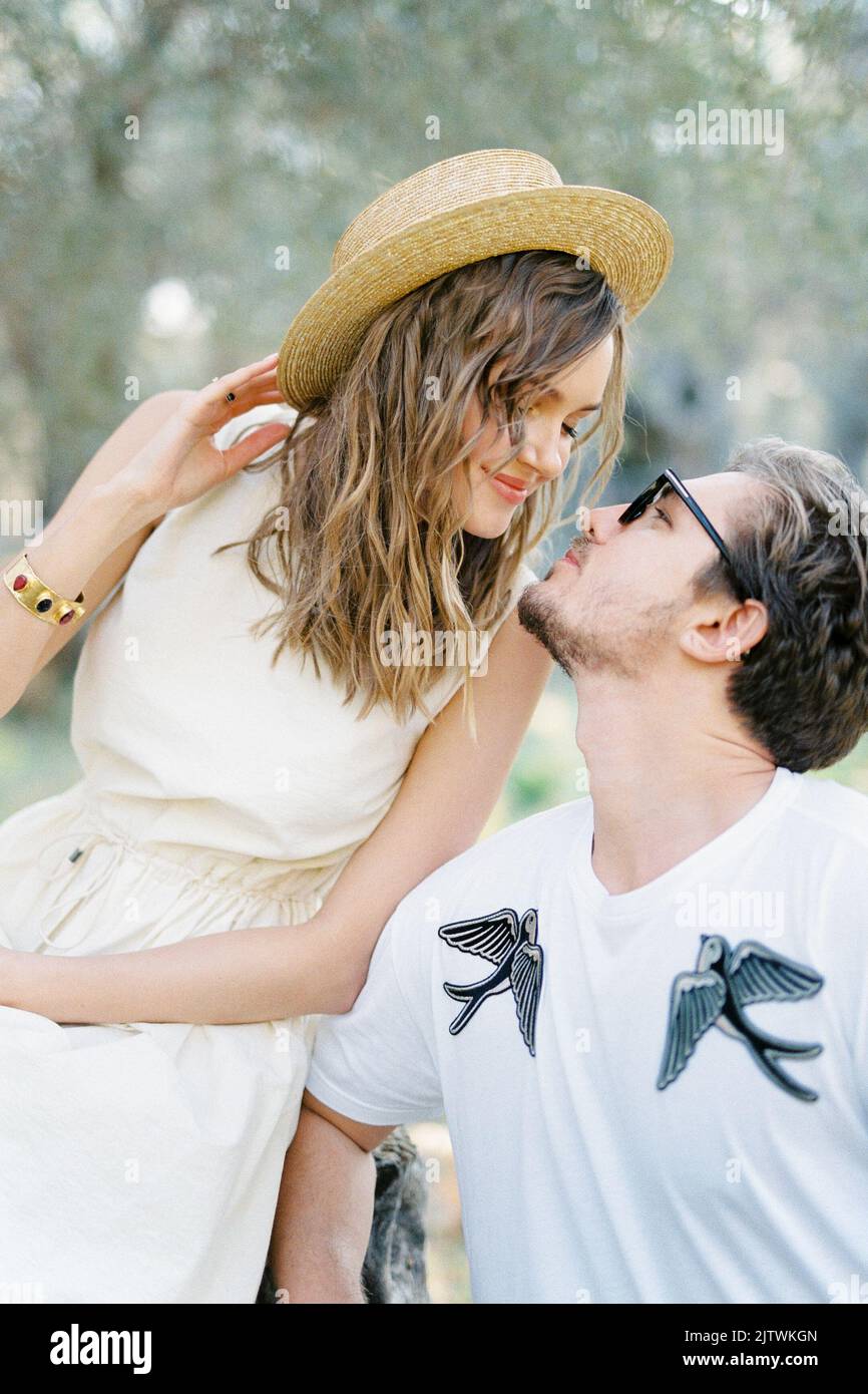 Young woman in a straw hat almost kisses a man leaning over him ...
