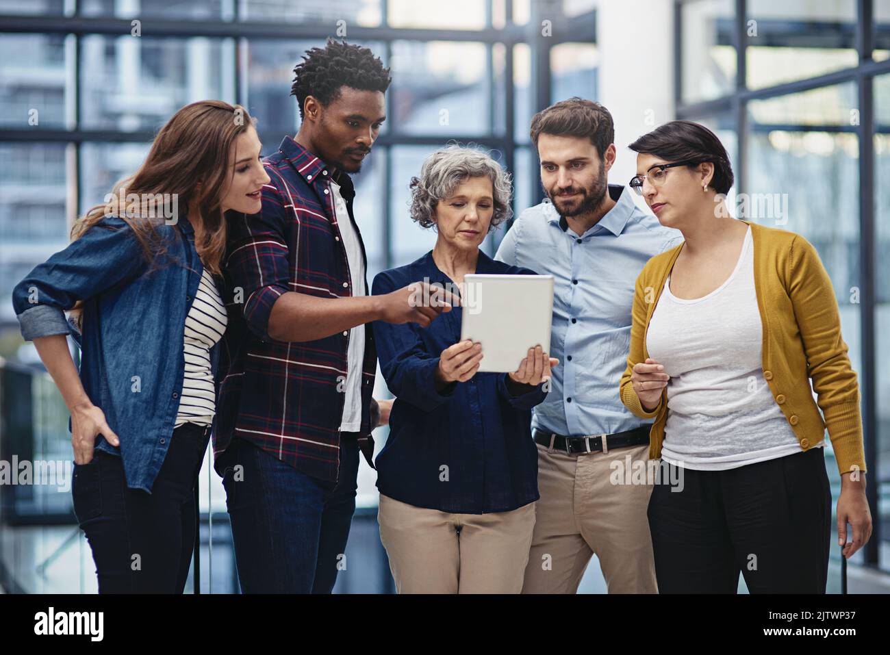 That looks interesting. a group of colleagues looking at a tablet in ...