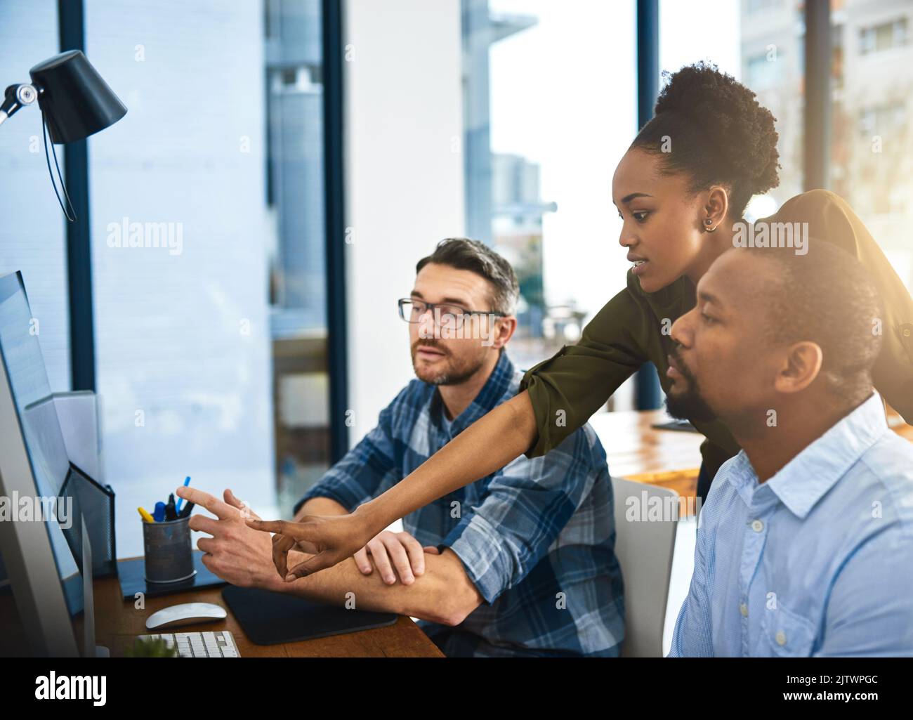 Let me see that. three businesspeople working around a computer in the ...