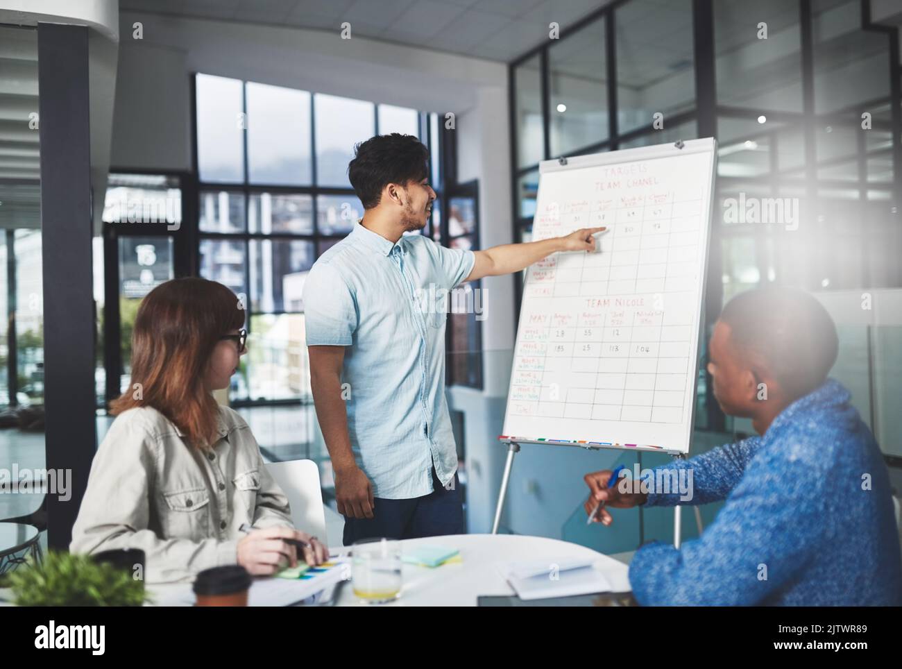 Keeping track of their progress. a young businessman using a whiteboard ...