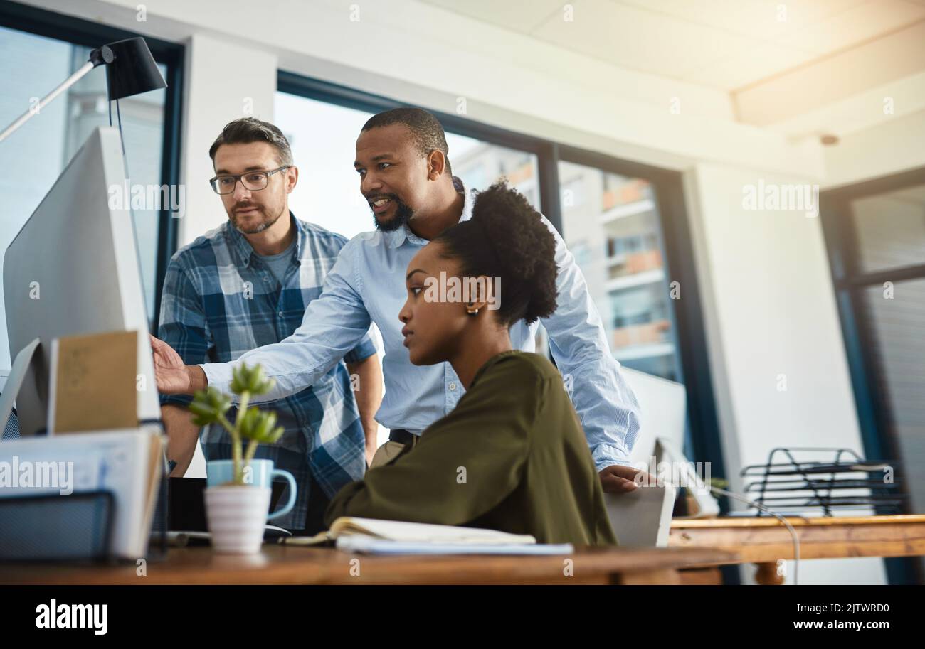 Zoom in on that. three businesspeople working around a computer in the ...