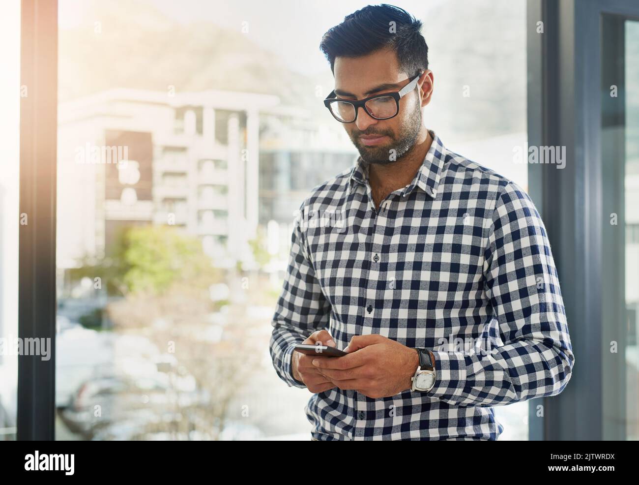 Accessing data right from his phone. a young businessman using his ...