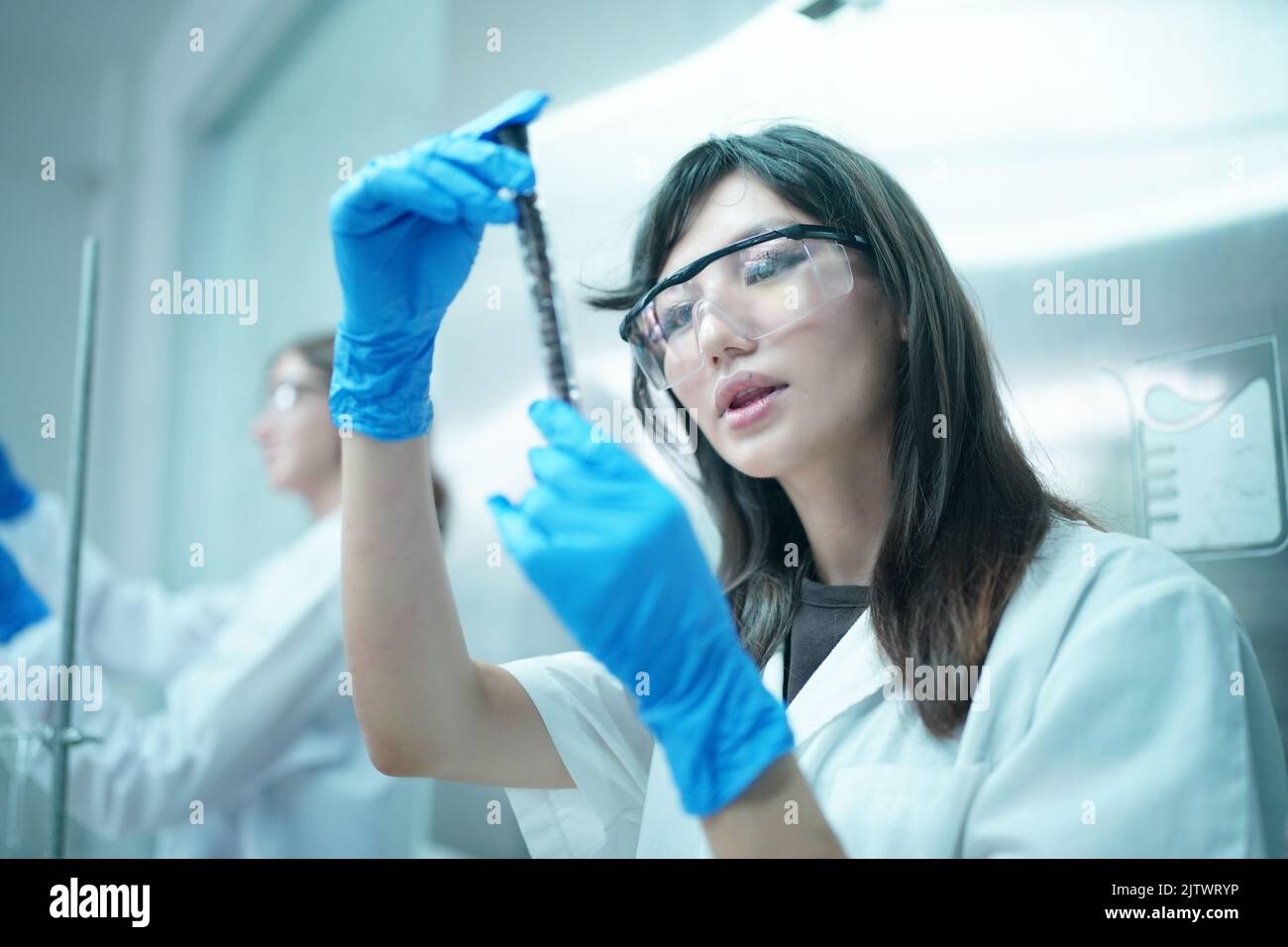 Young scientist in white lab coat working with binocular microscope in ...