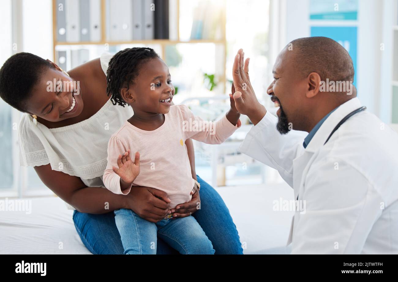 Healthcare, mother and girl gives doctor high five in a doctors office ...