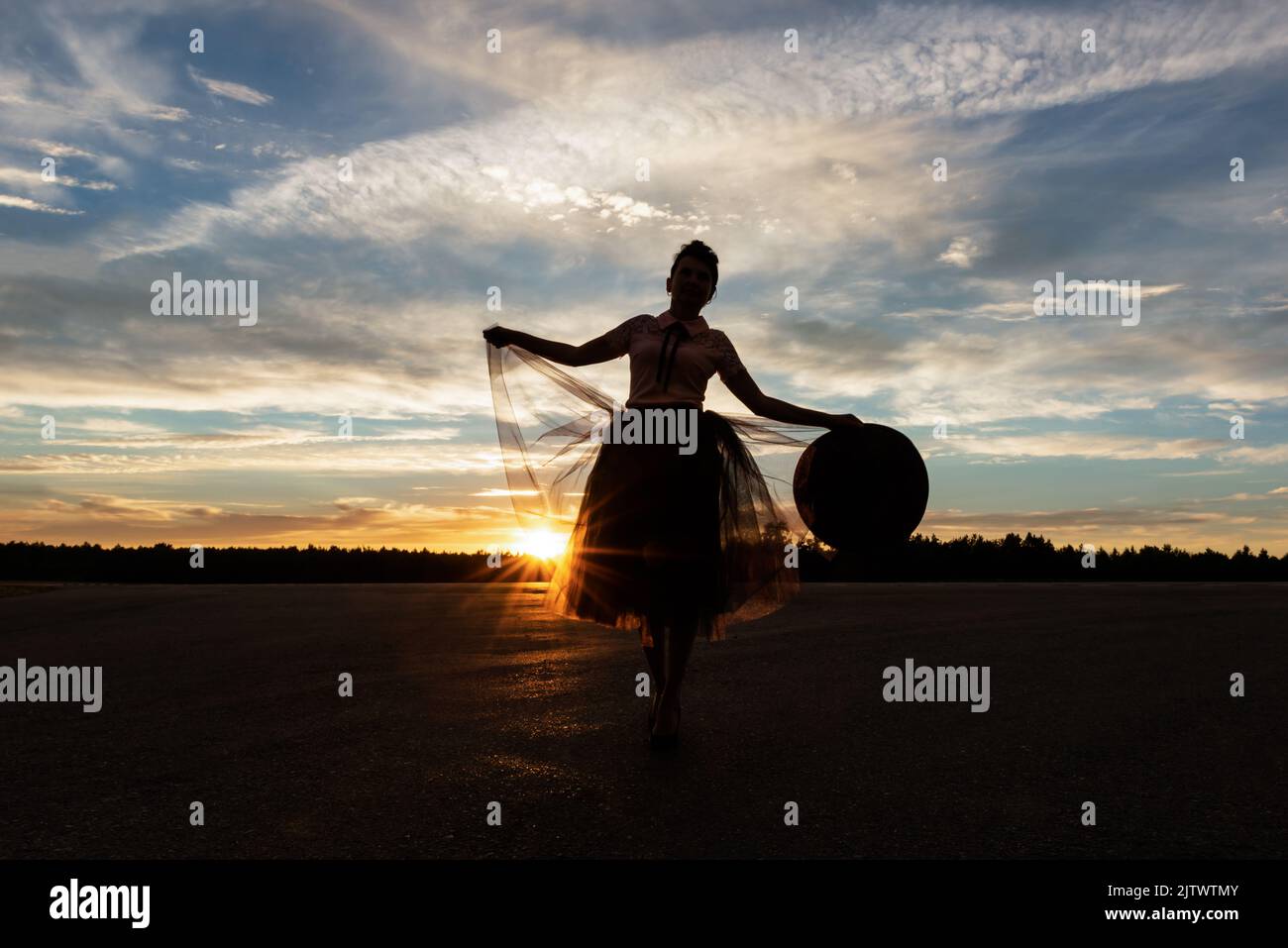 Sunset fairy has fun in evening rays of sun holding edge of tutu skirt ...