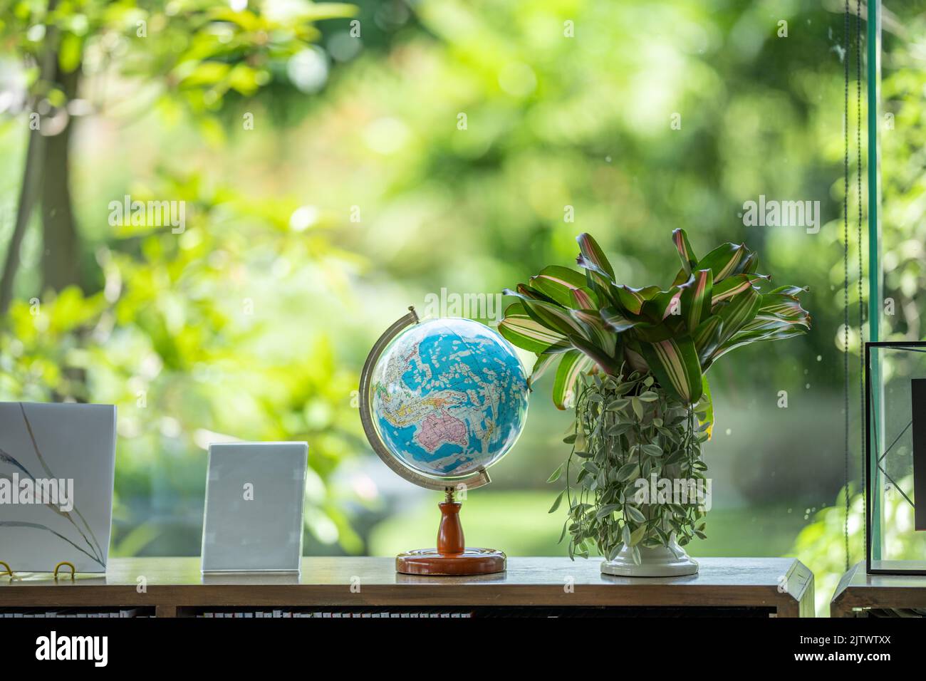 A miniature replica of the globe is placed on wooden table beside ...