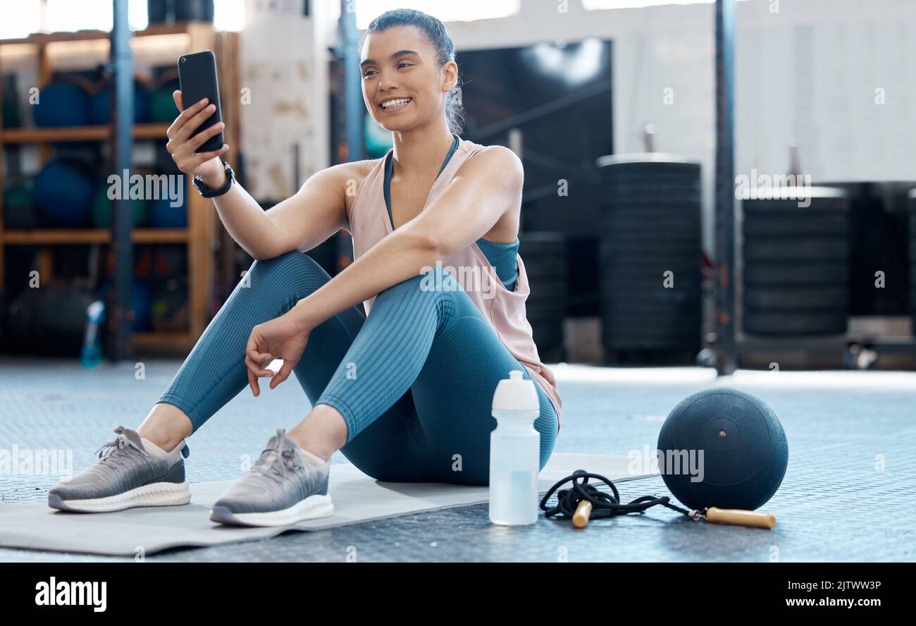 Woman taking selfie with phone after workout at the gym, reading social ...