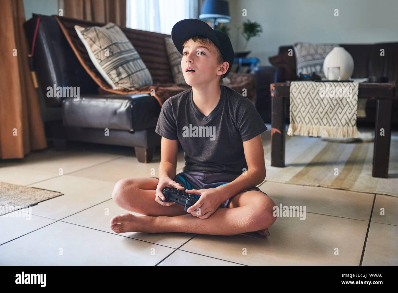 Focused on his game. Full length shot of a young boy playing video ...