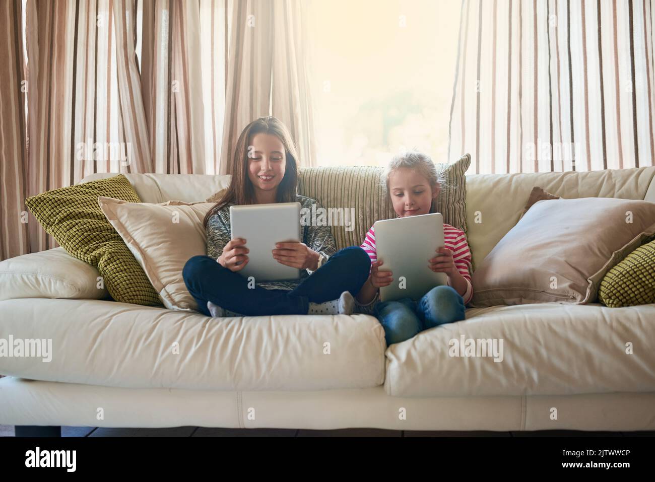 Technology is a great babysitter. two little girls playing with their ...
