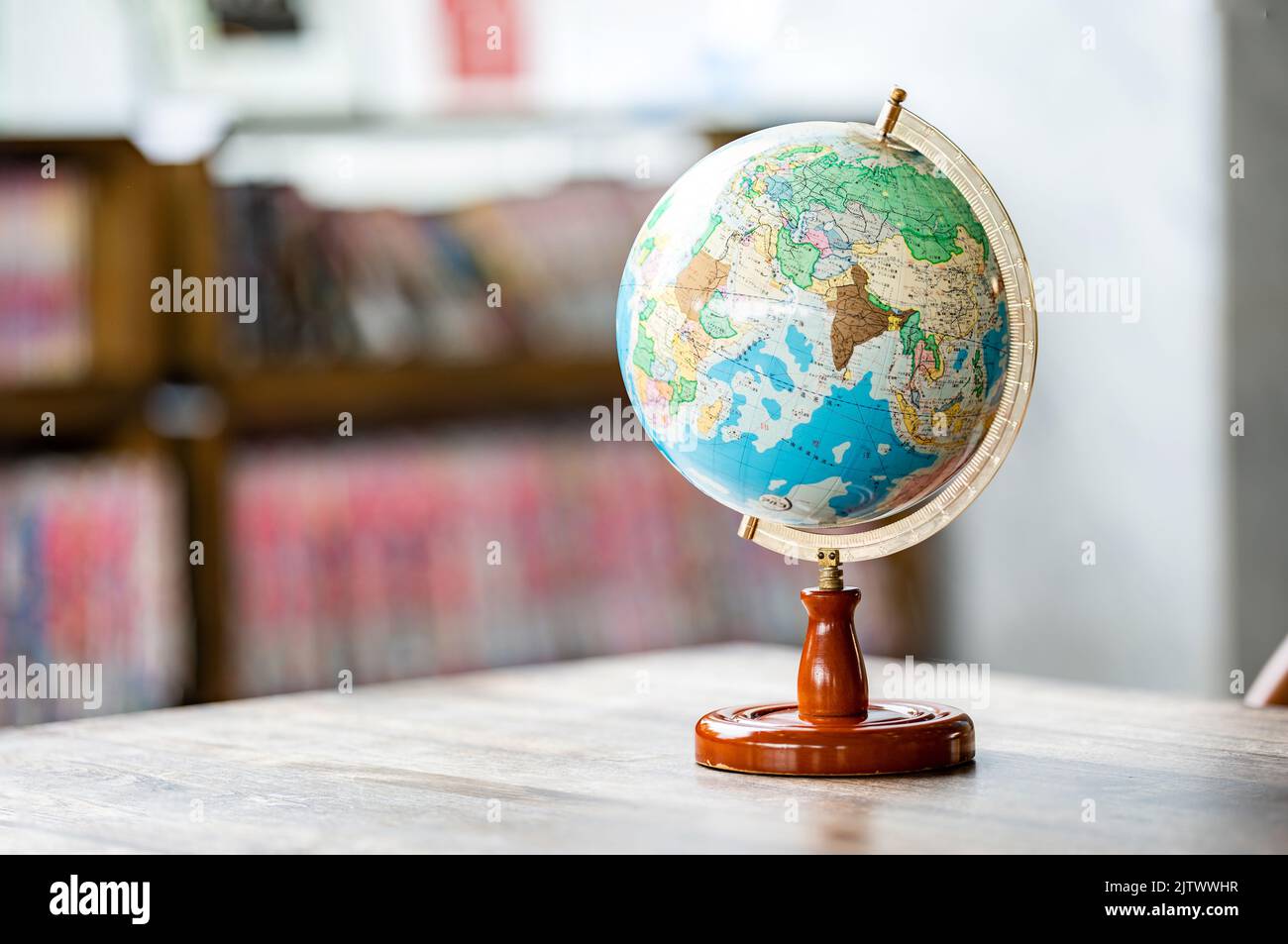A miniature replica of the globe is placed on wooden table beside ...
