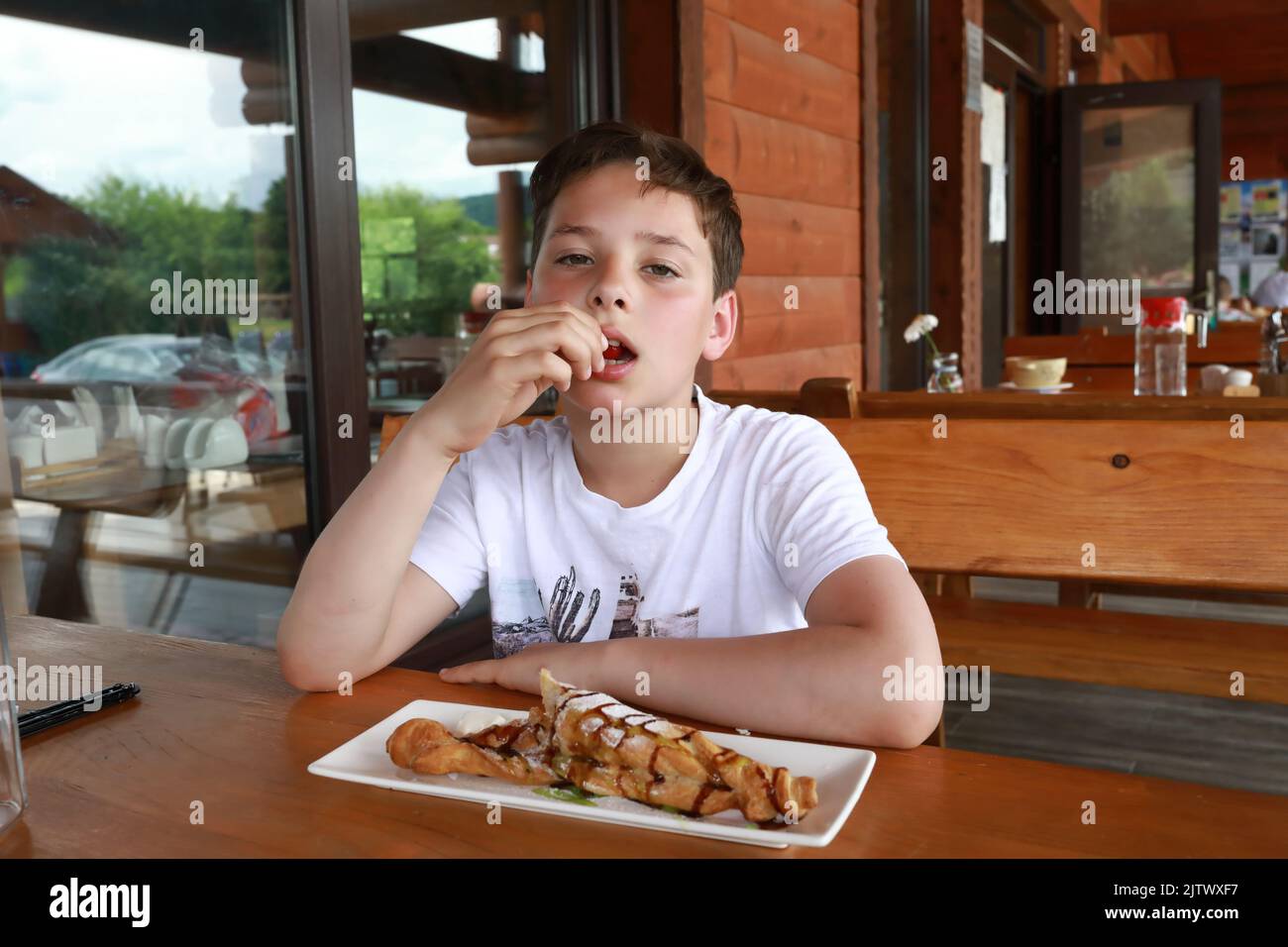 Portrait of child eating strudel on terrace of restaurant Stock Photo ...