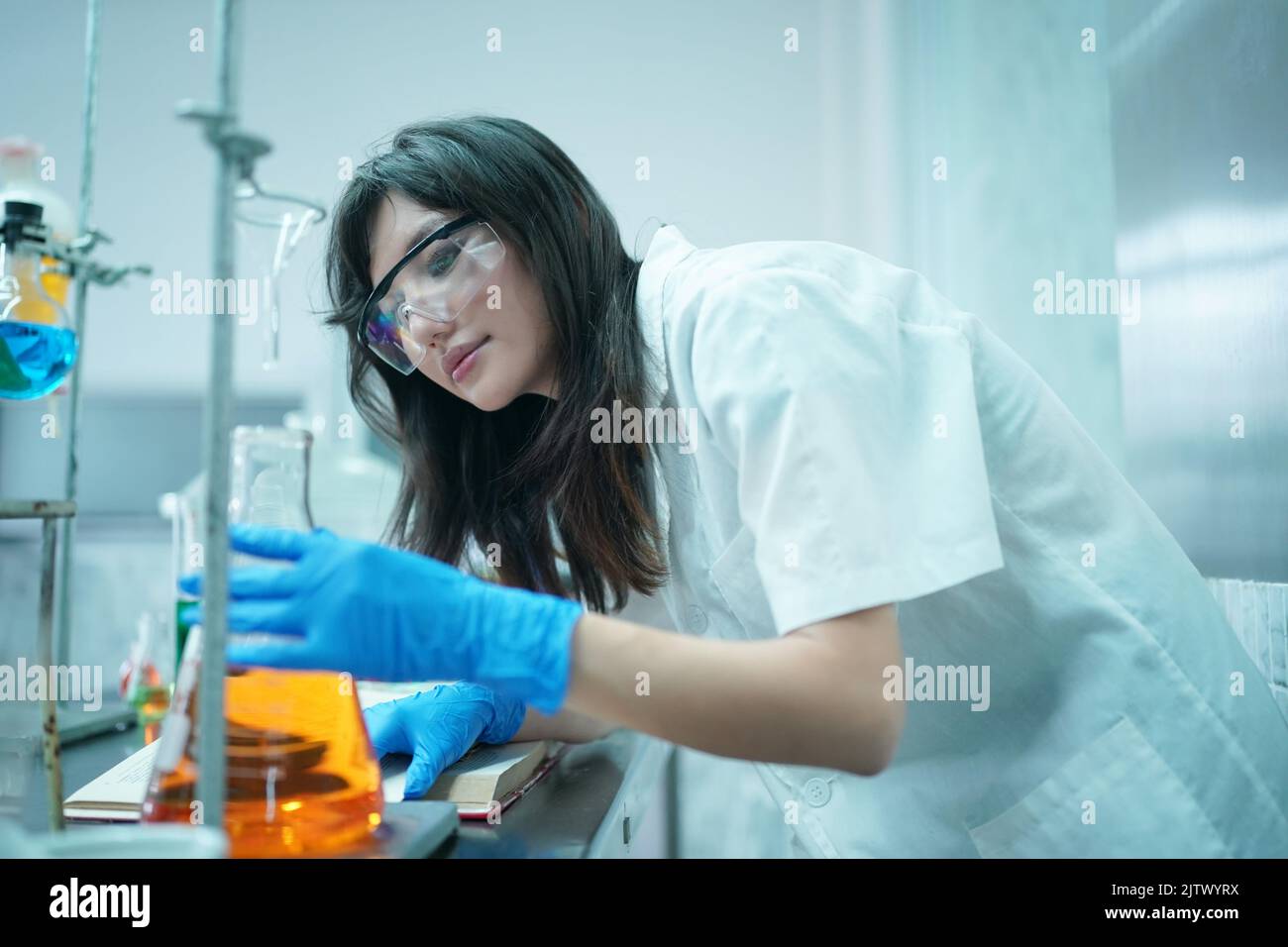 Young scientist in white lab coat working with binocular microscope in ...