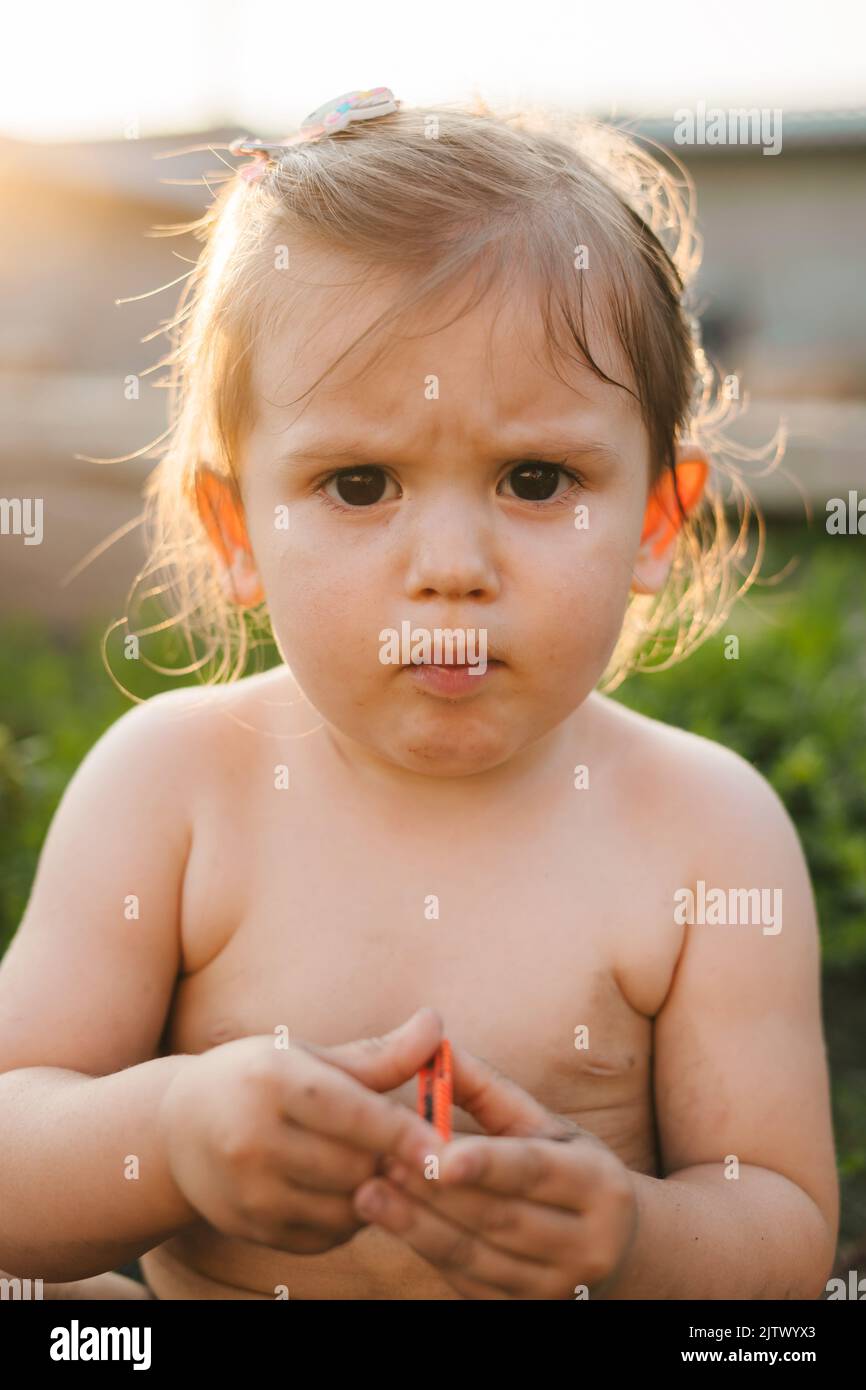 Baby girl with a concentrated face looking at the camera to show what ...