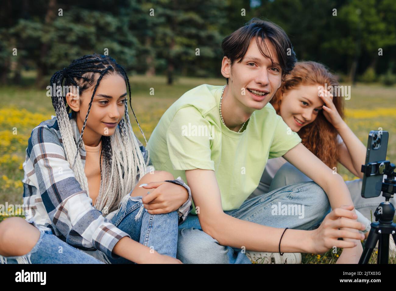 A group of three people using a tripod and phone to take a group photo ...
