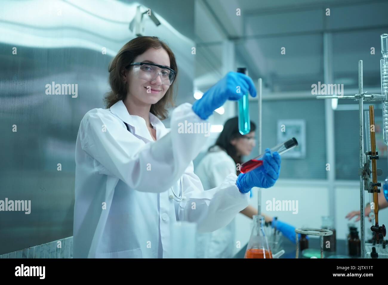Young scientist in white lab coat working with binocular microscope in ...
