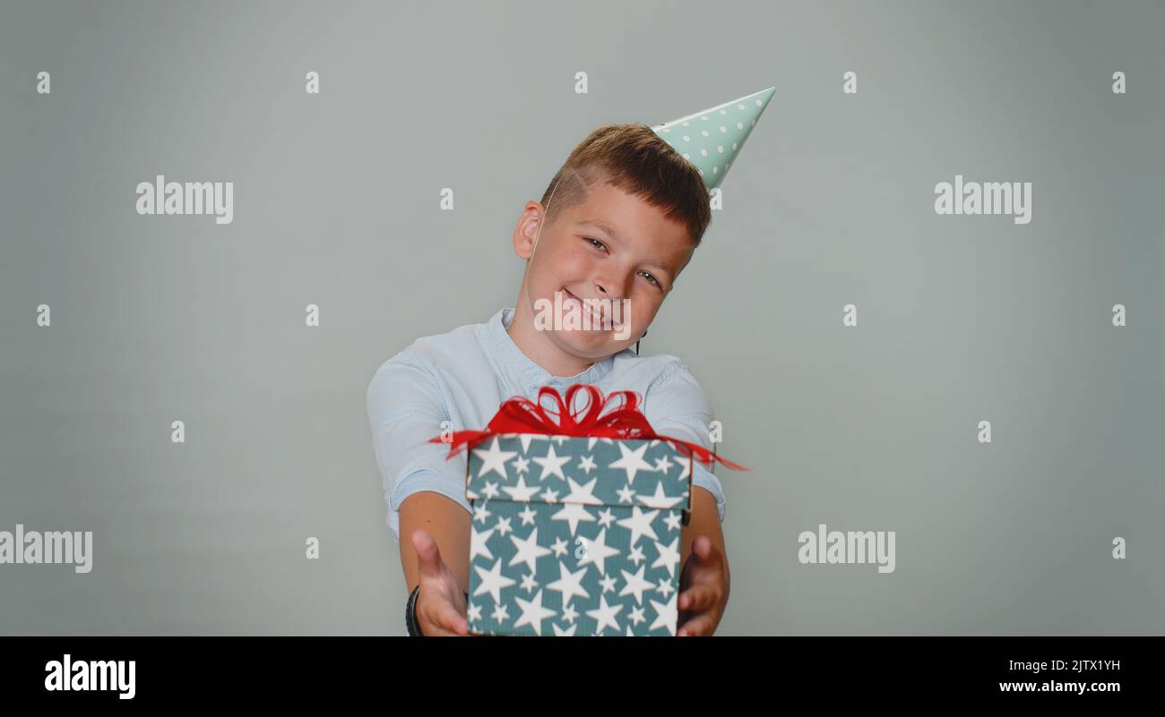 Smiling toddler young boy presenting birthday gift box stretches out ...