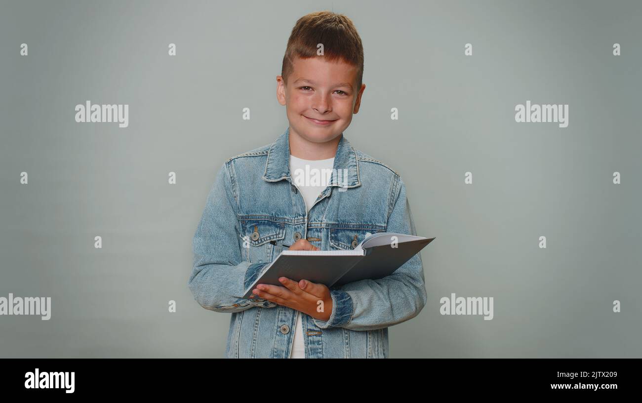 Thoughtful toddler kid boy in jacket making notes, writing down ...