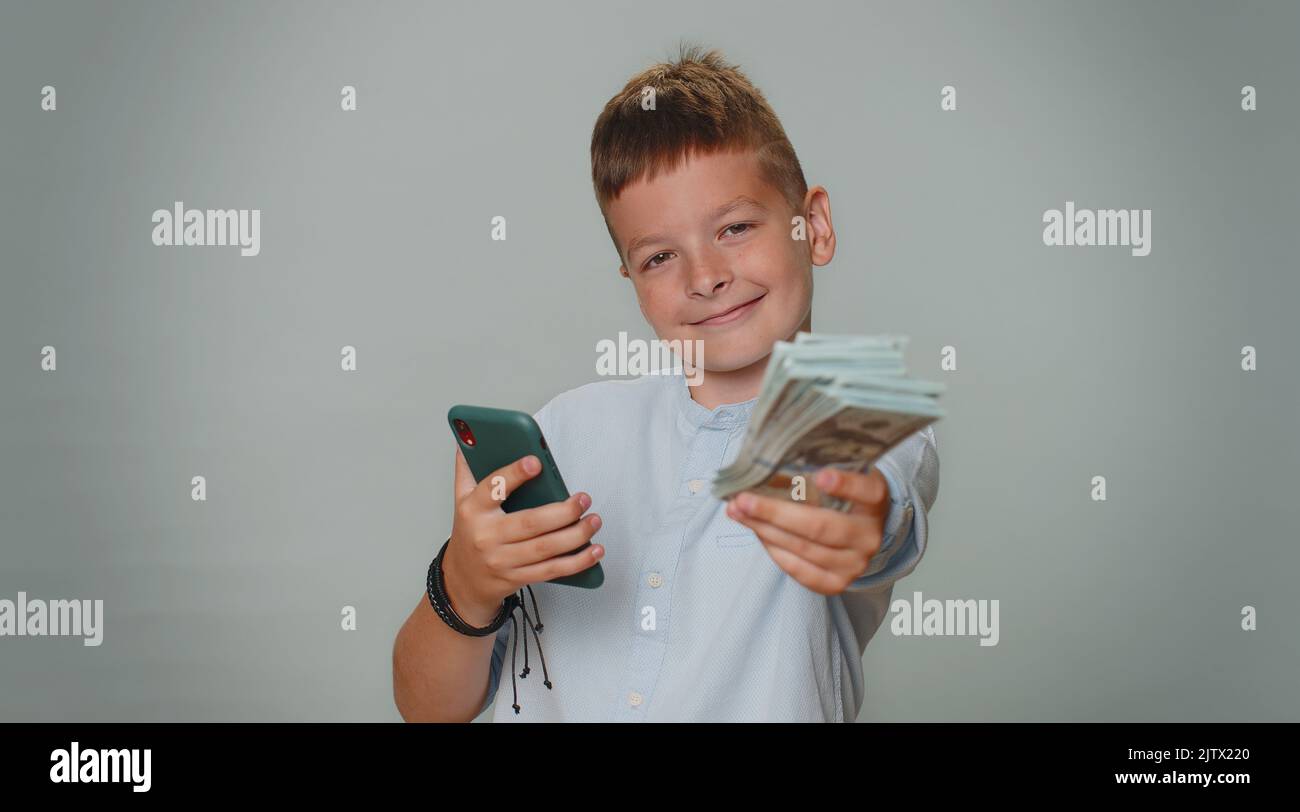 Rich toddler boy looking smartphone display sincerely rejoicing win ...