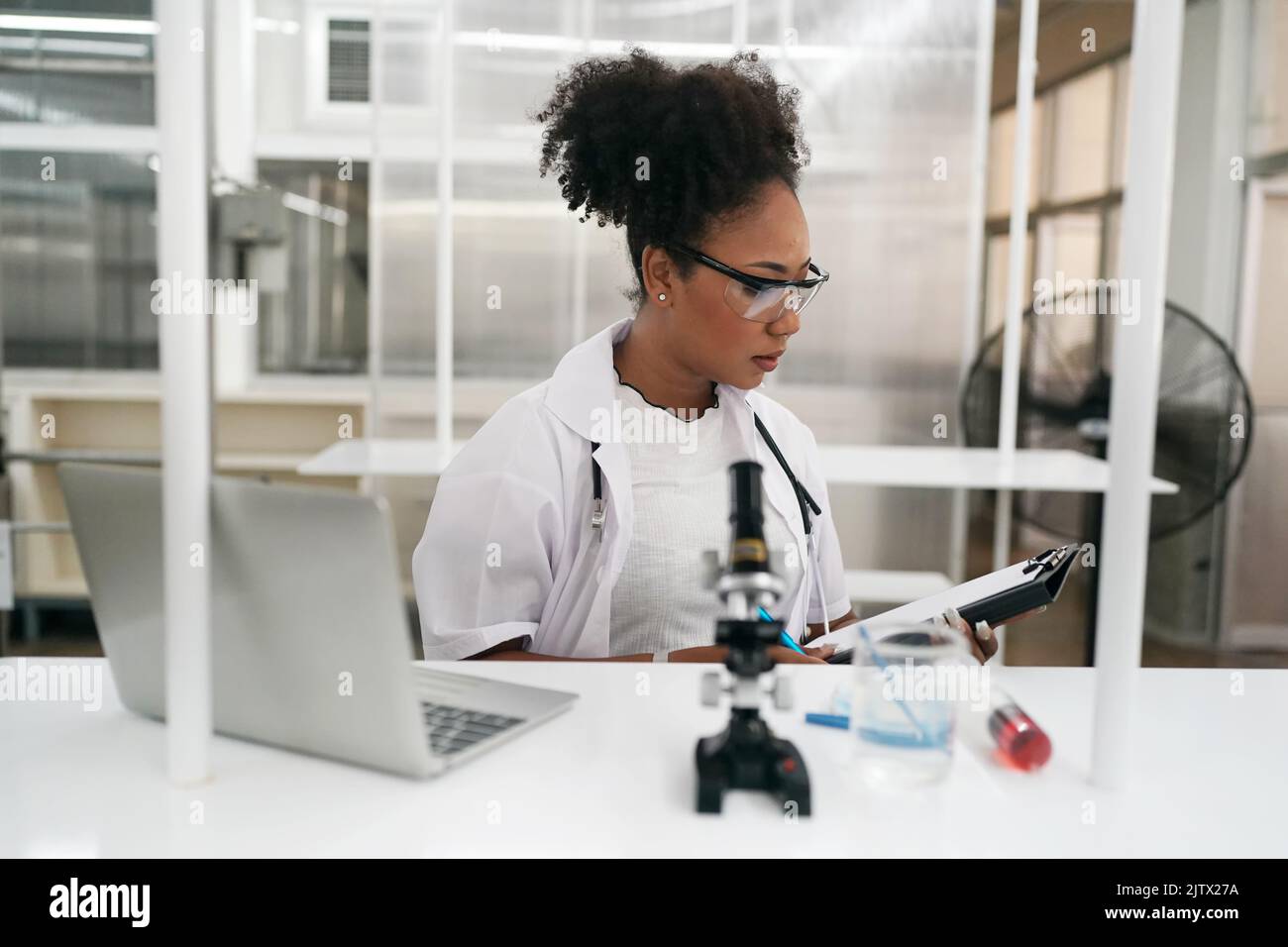 Young scientist in white lab coat working with binocular microscope in ...