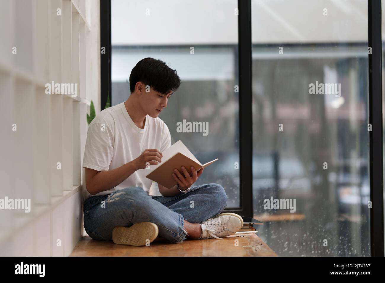 Young Asian man reading a book at cafe. Lifestyle concept Stock Photo ...