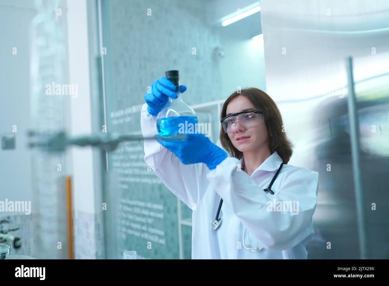 Young scientist in white lab coat working with binocular microscope in ...