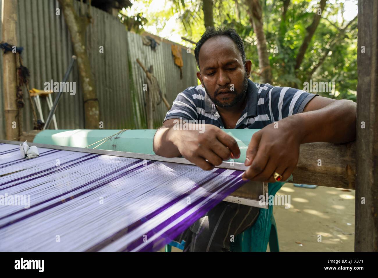 A man prepares the warp threads for weaving traditional Lungi in ...