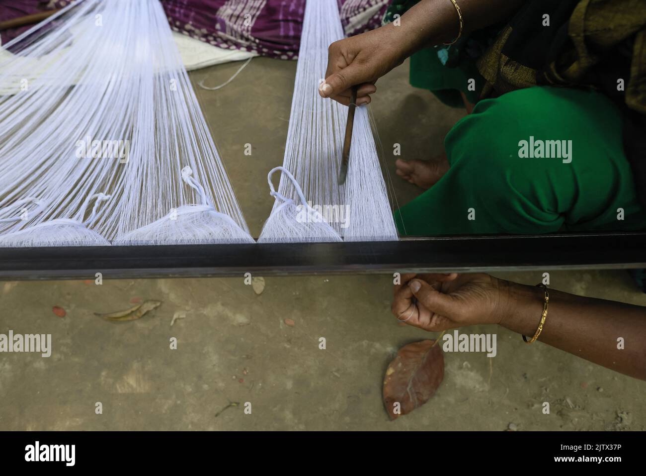 A man prepares the warp threads for weaving traditional Lungi in handloom in Keraniganj, near ...