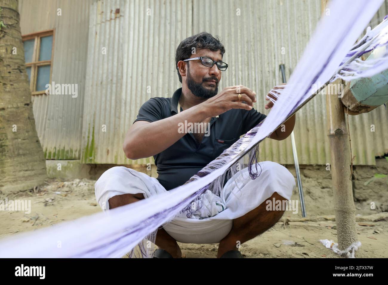 A man prepares the warp threads for weaving traditional Lungi in ...