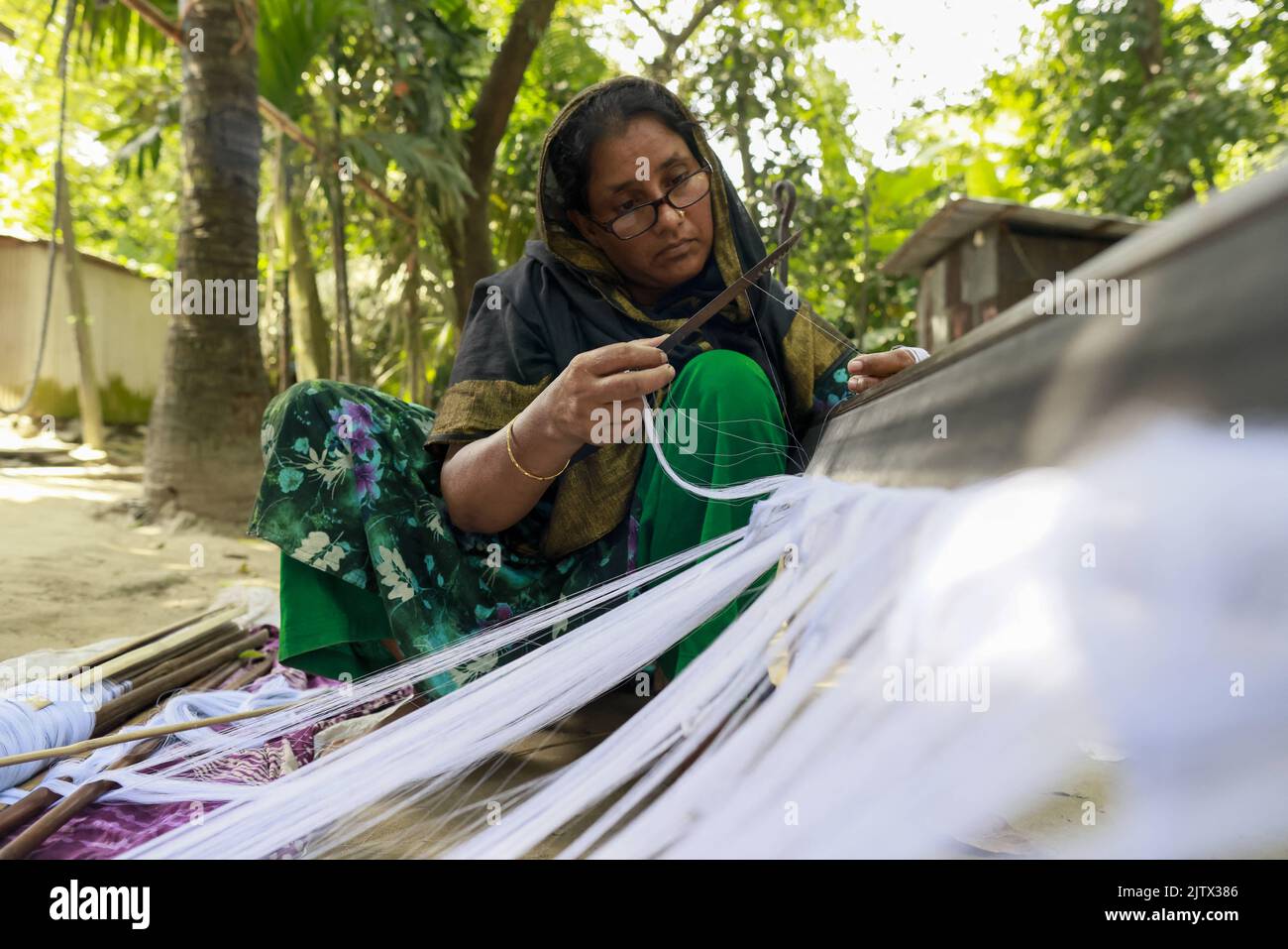 A man prepares the warp threads for weaving traditional Lungi in ...