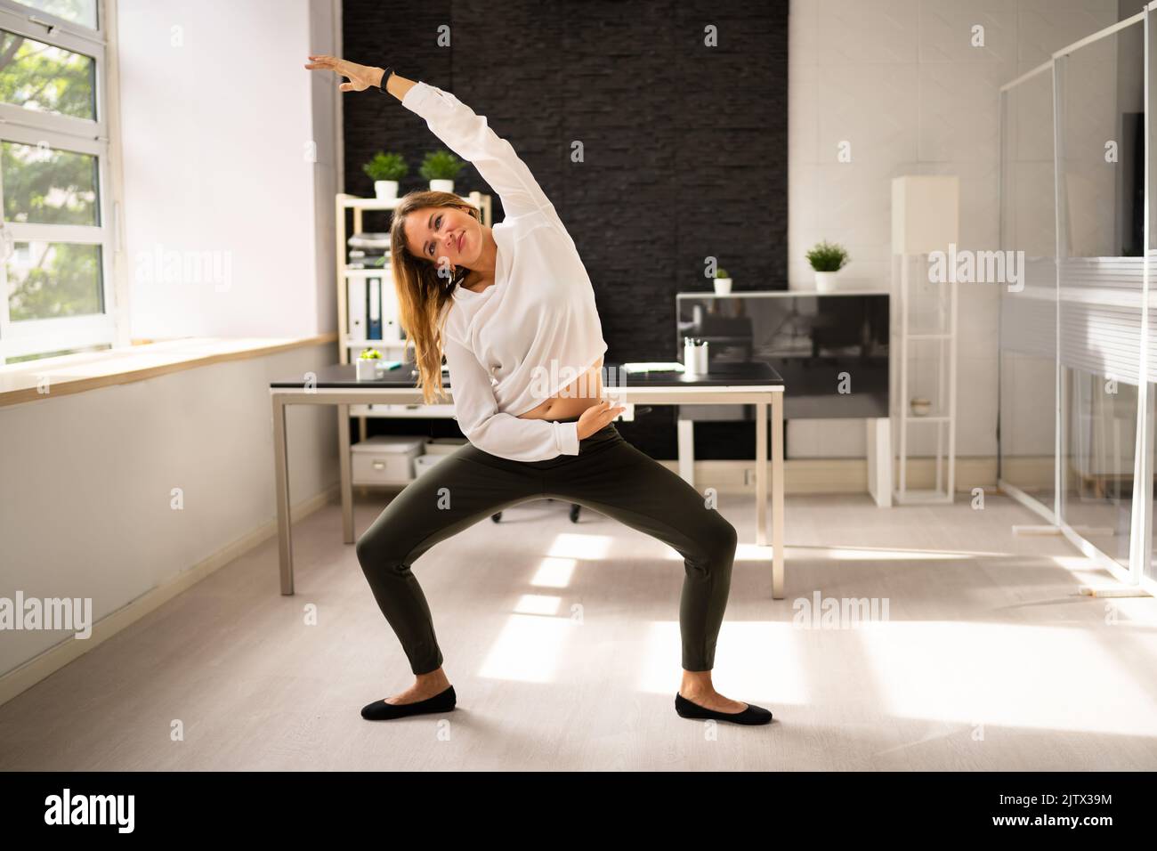 Stretch Exercise Standing Near Desk In Office Stock Photo - Alamy