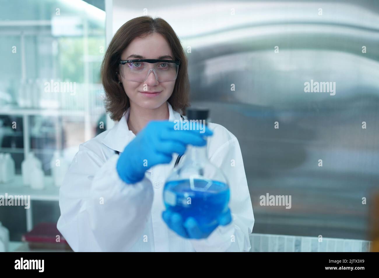 Young scientist in white lab coat working with binocular microscope in ...
