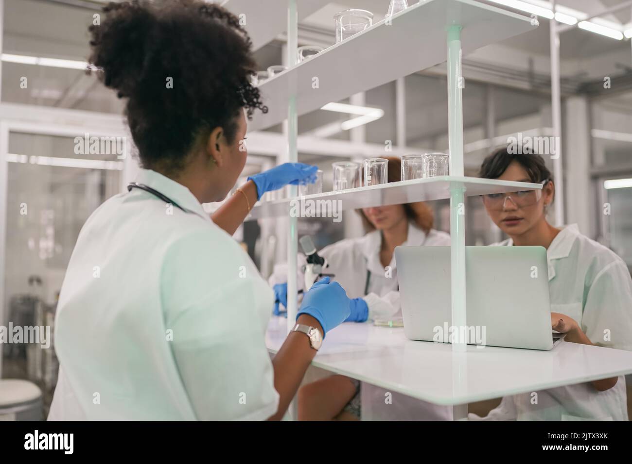 Young scientist in white lab coat working with binocular microscope in ...